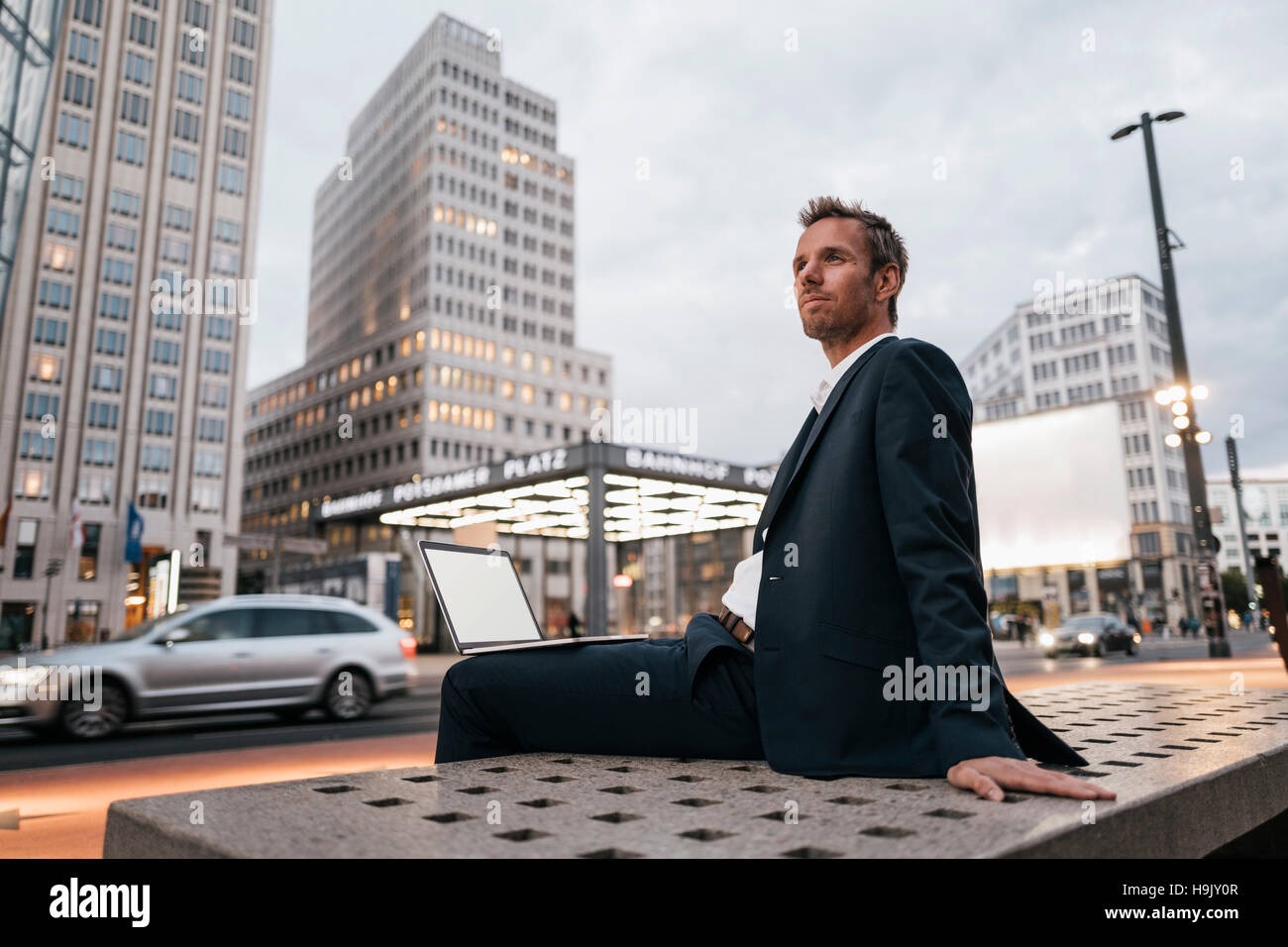 Germany, Berlin, Potsdamer Platz, businessman sitting on bench with ...