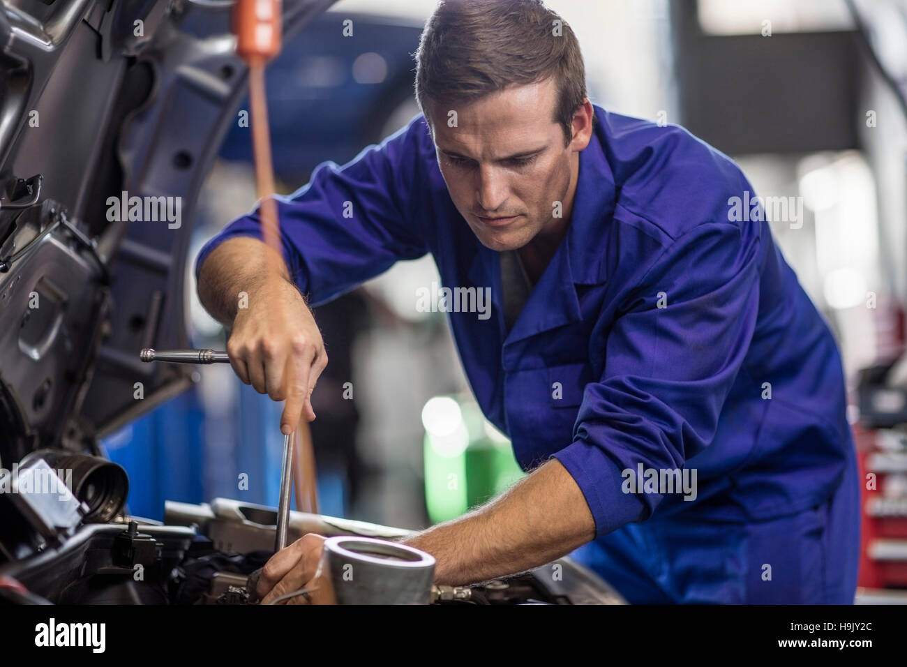 Car mechanic in a workshop repairing car Stock Photo - Alamy