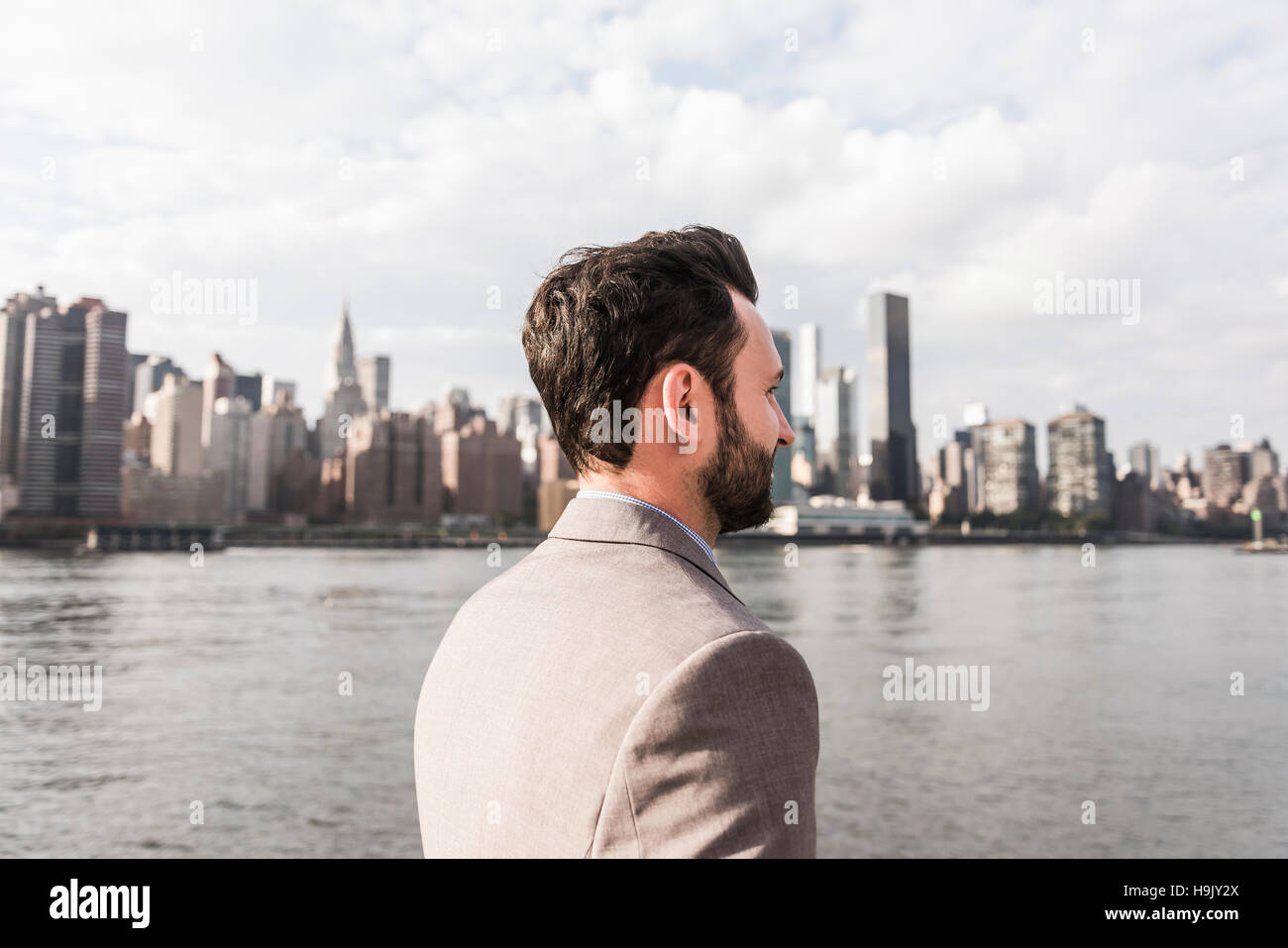 USA, New York City, man at East River in front of skyline of Manhattan ...