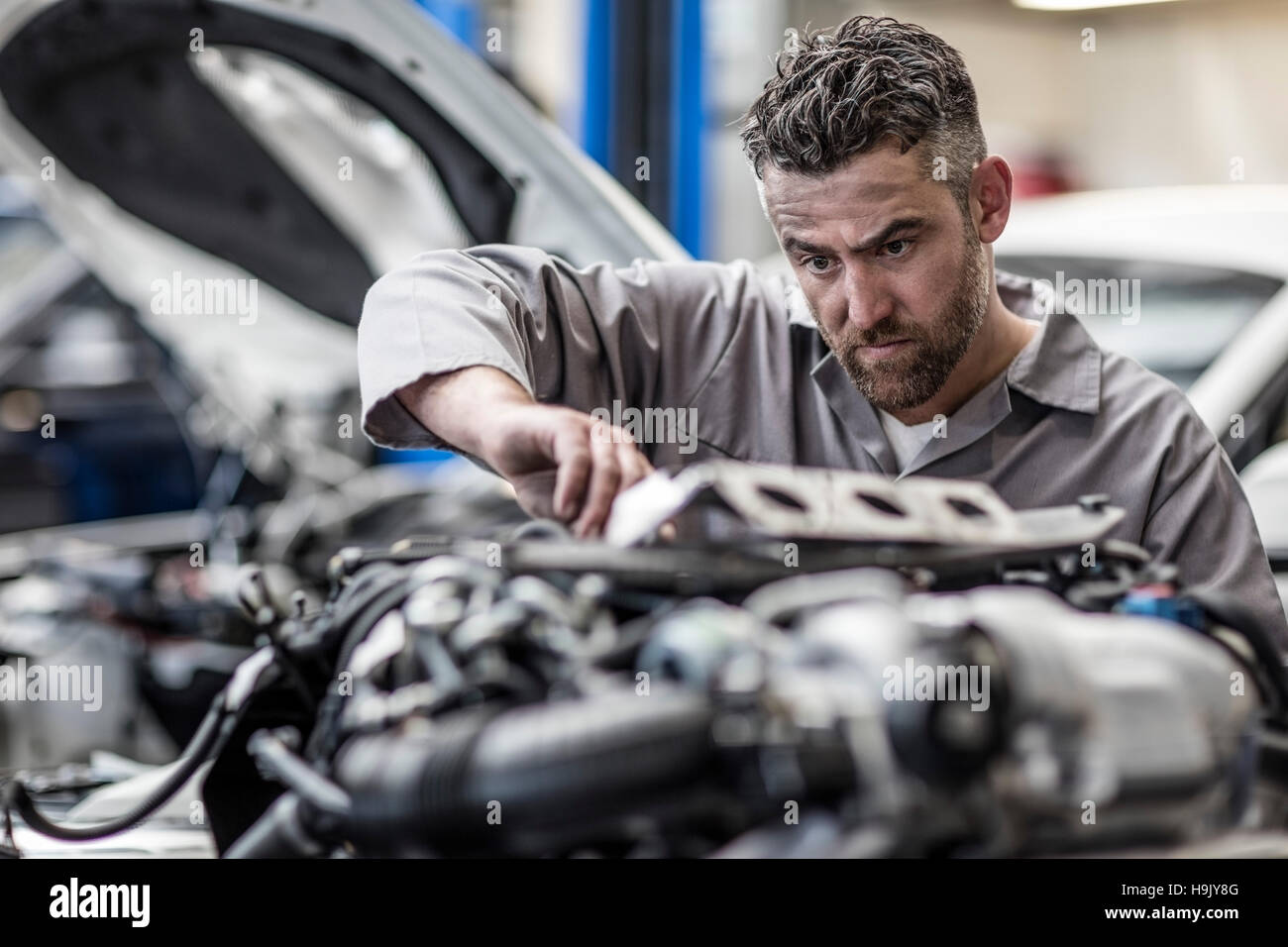 Car mechanic in a workshop working on engine Stock Photo - Alamy