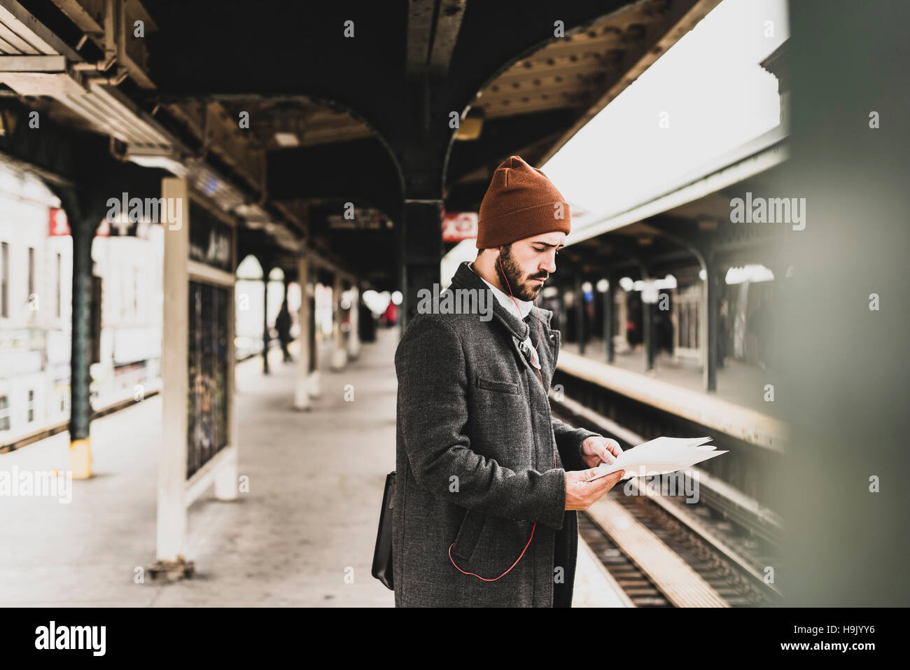 Young man waiting at metro station platform, reading documents Stock ...
