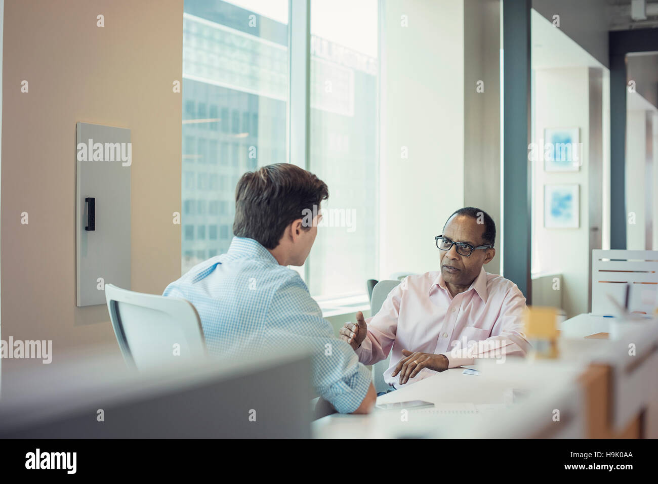 Two businessmen talking together in office Stock Photo - Alamy