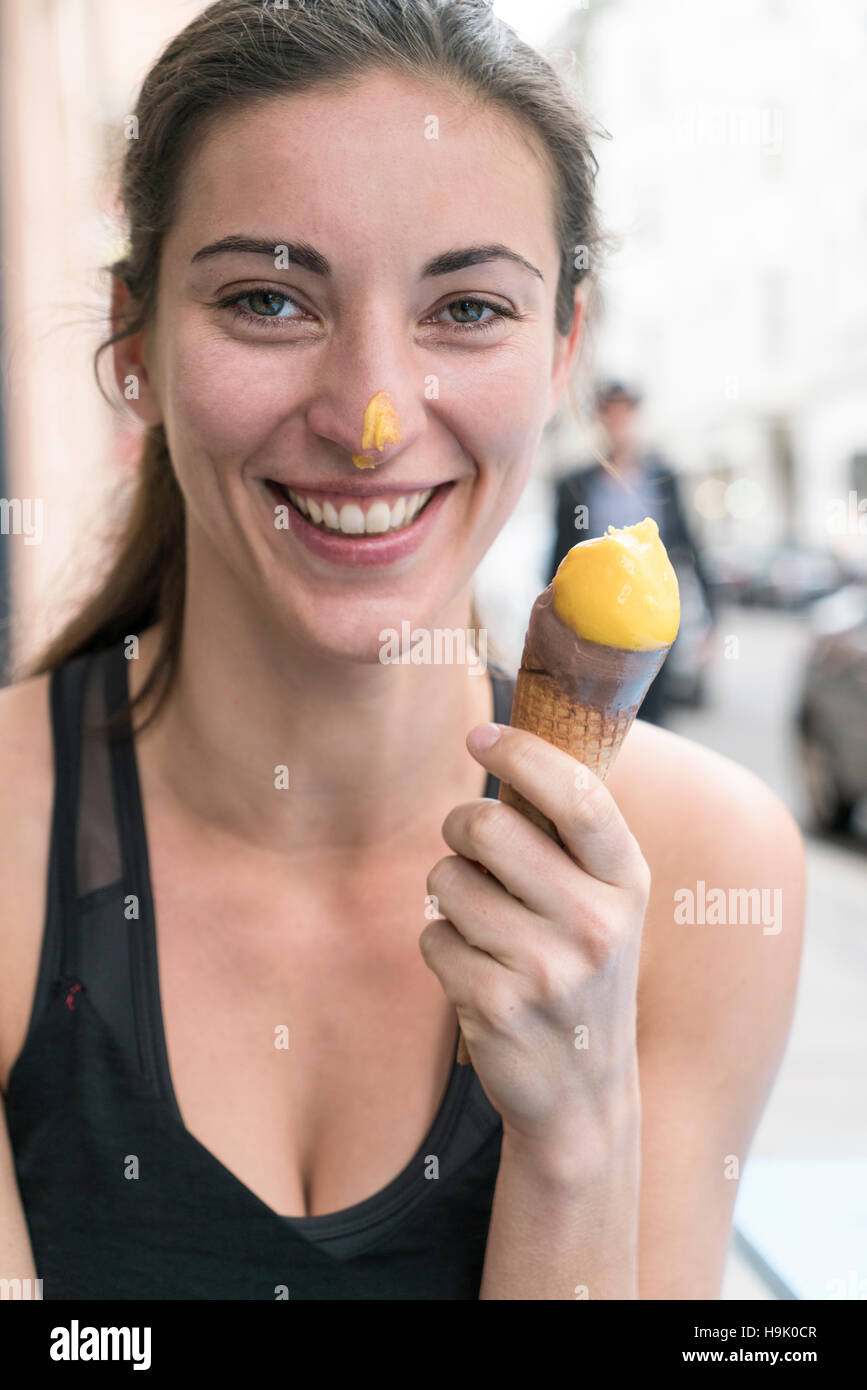 Portrait of smiling young woman with ice cream cone and ice cream at ...