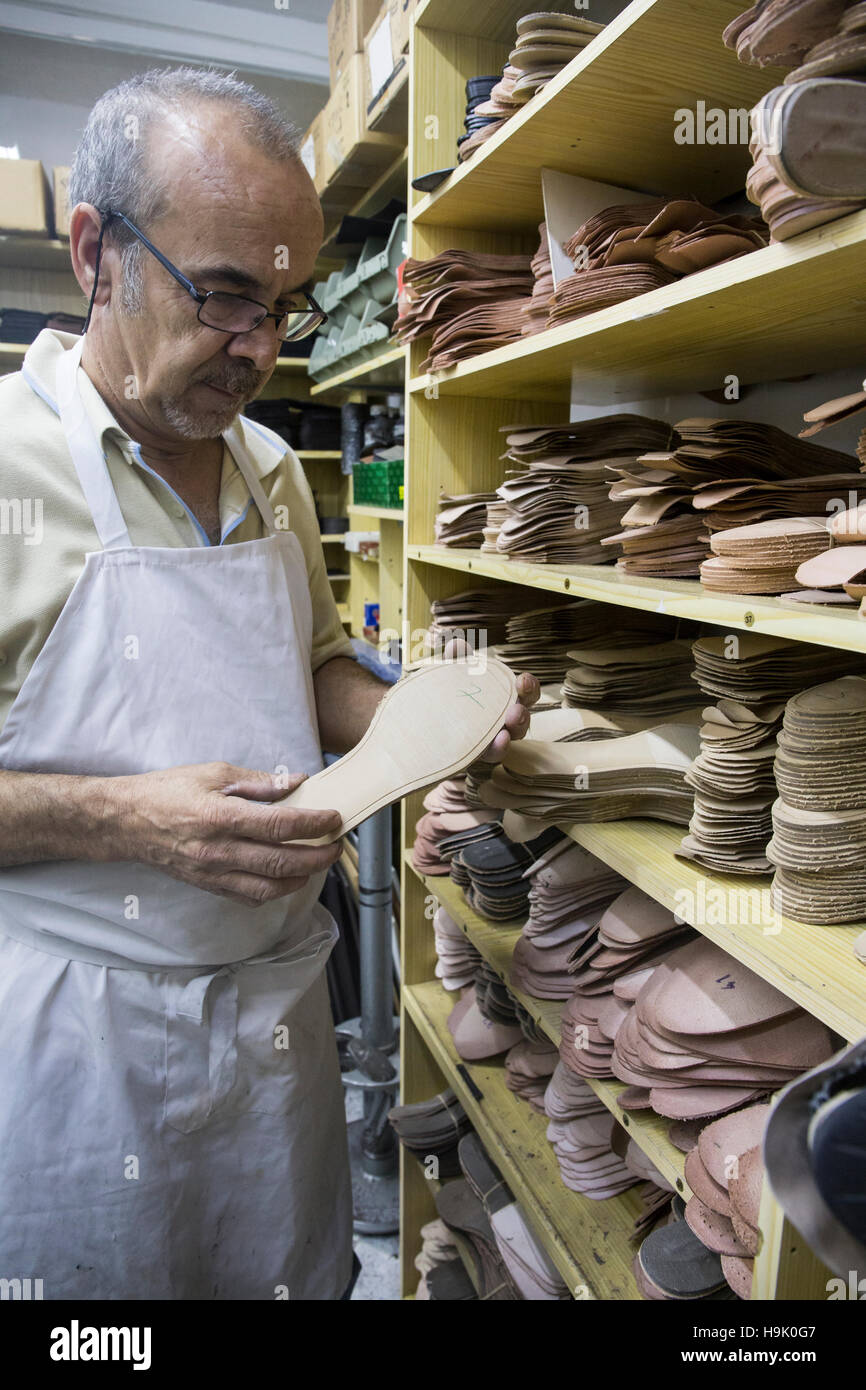 Shoemaker selecting shoe soles from a shelf in his workshop Stock Photo ...