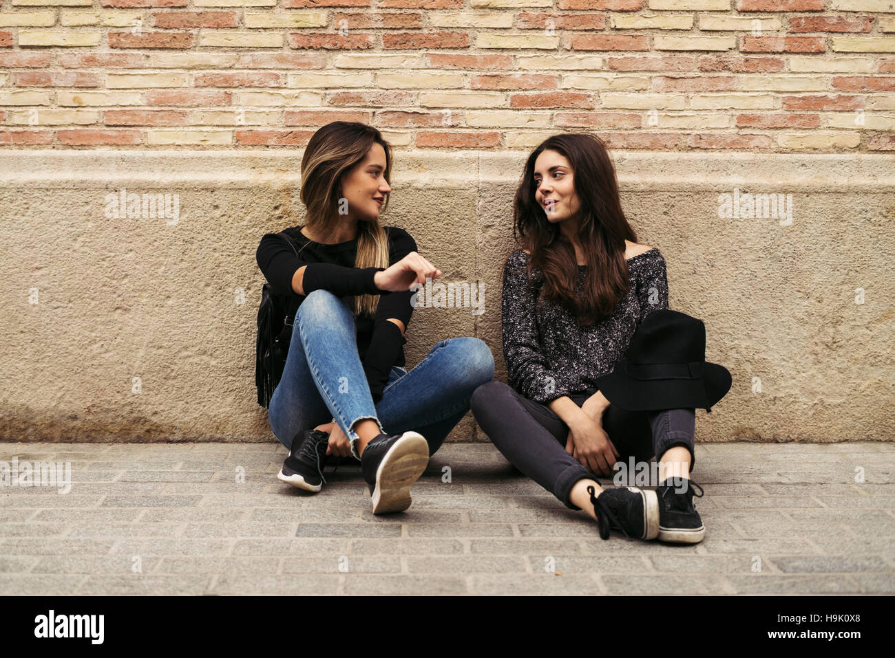 Two best friends sitting in front of facade talking together Stock ...