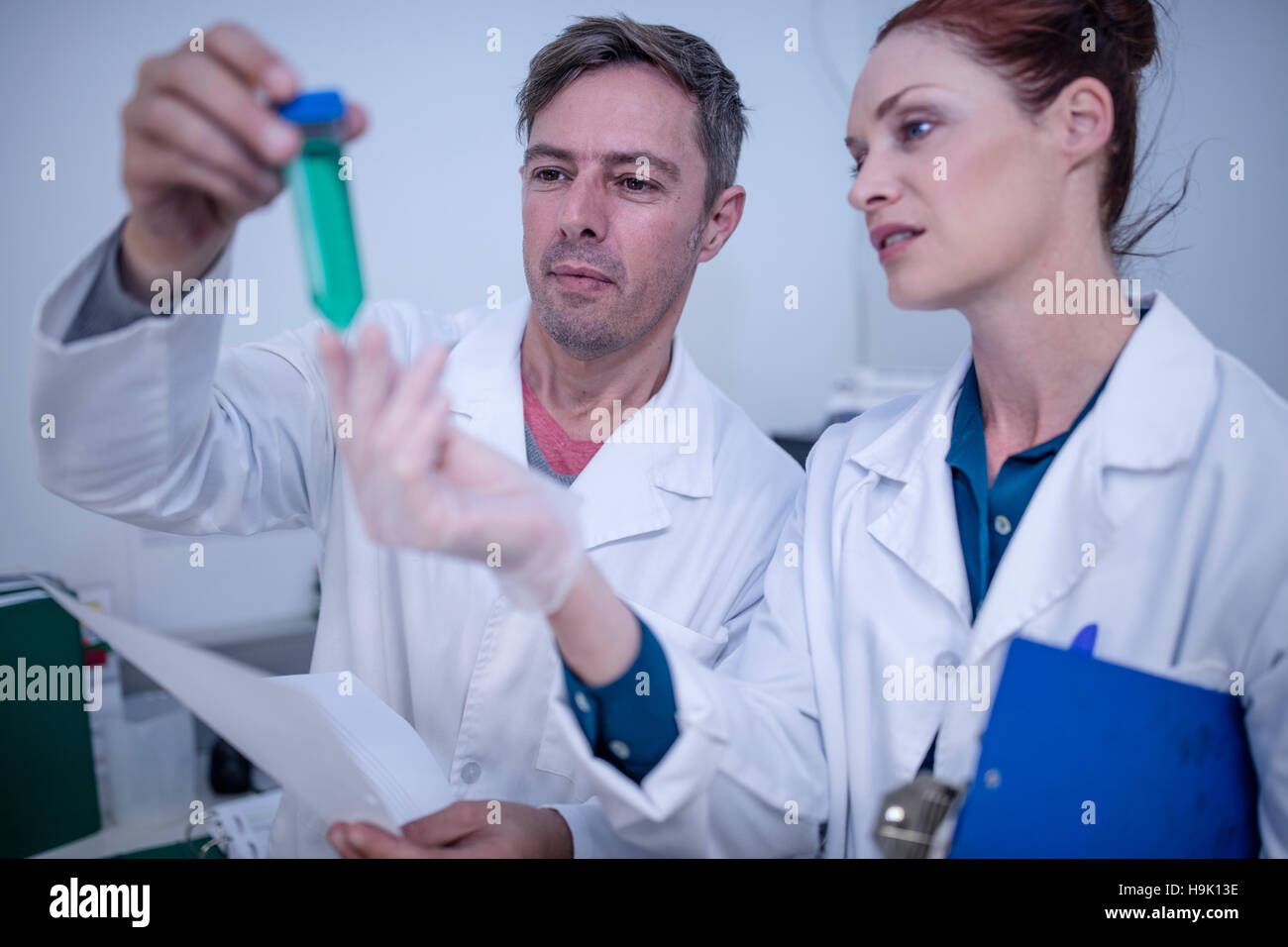 Scientists looking at sample in test tube in laboratory Stock Photo - Alamy