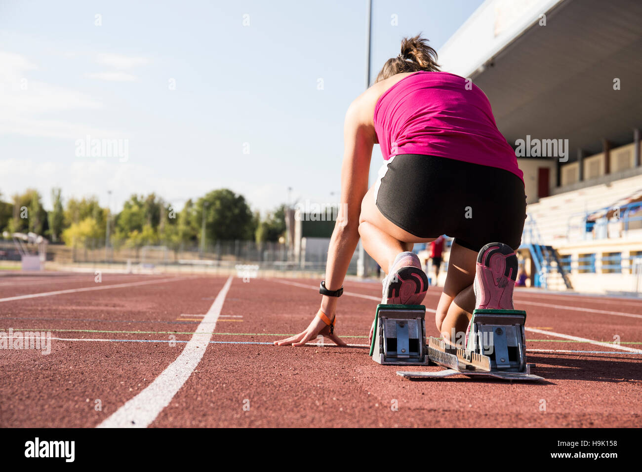 Female runner on tartan track in starting position Stock Photo - Alamy