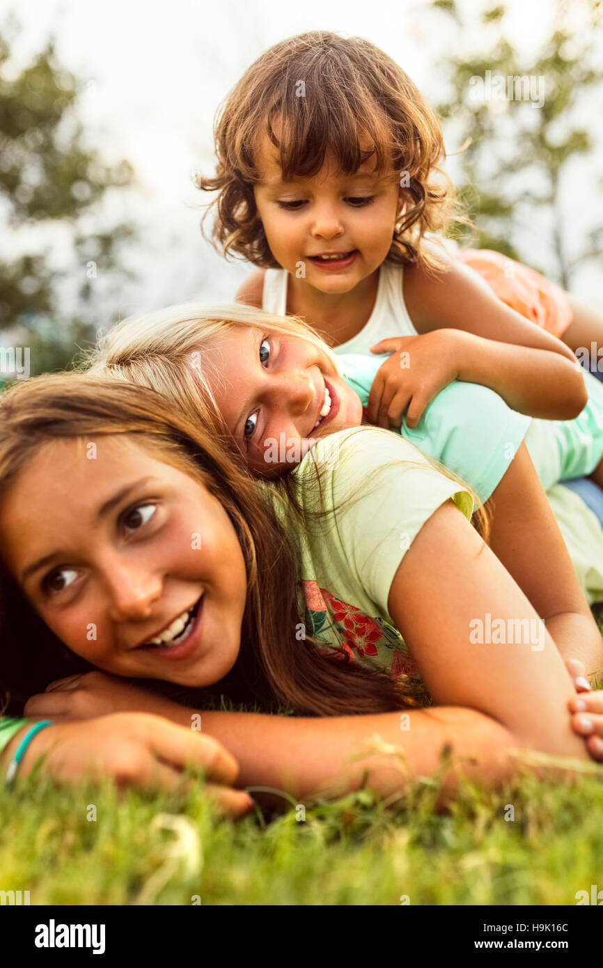 Three girls playing together on a meadow Stock Photo - Alamy