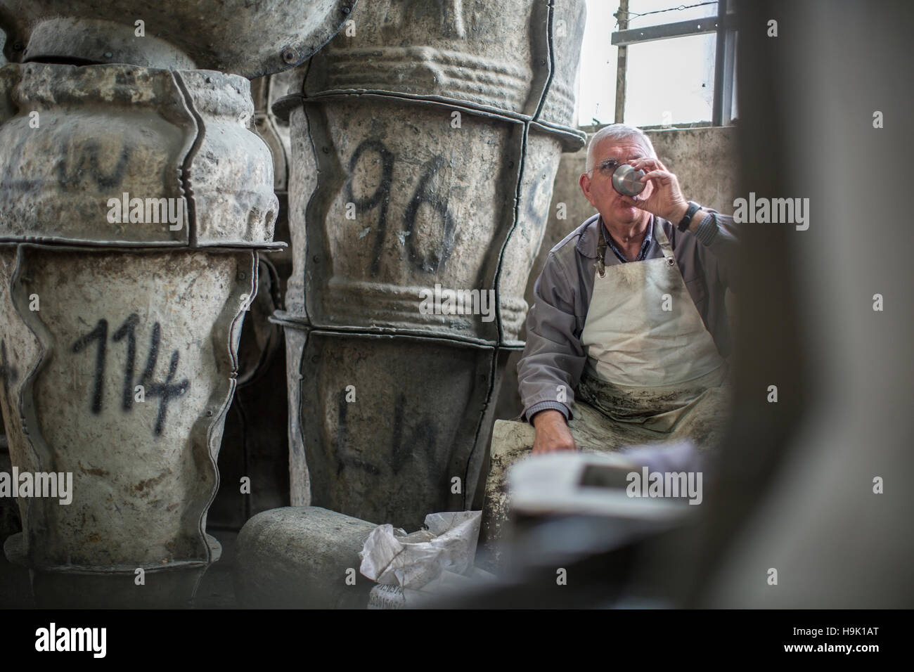 Worker having a coffe break in industrial pot factory Stock Photo - Alamy
