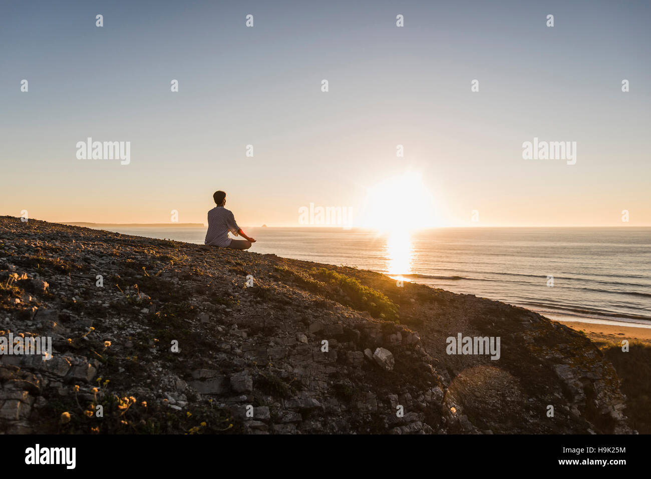 Back view of woman meditating on cliff at sunset Stock Photo - Alamy
