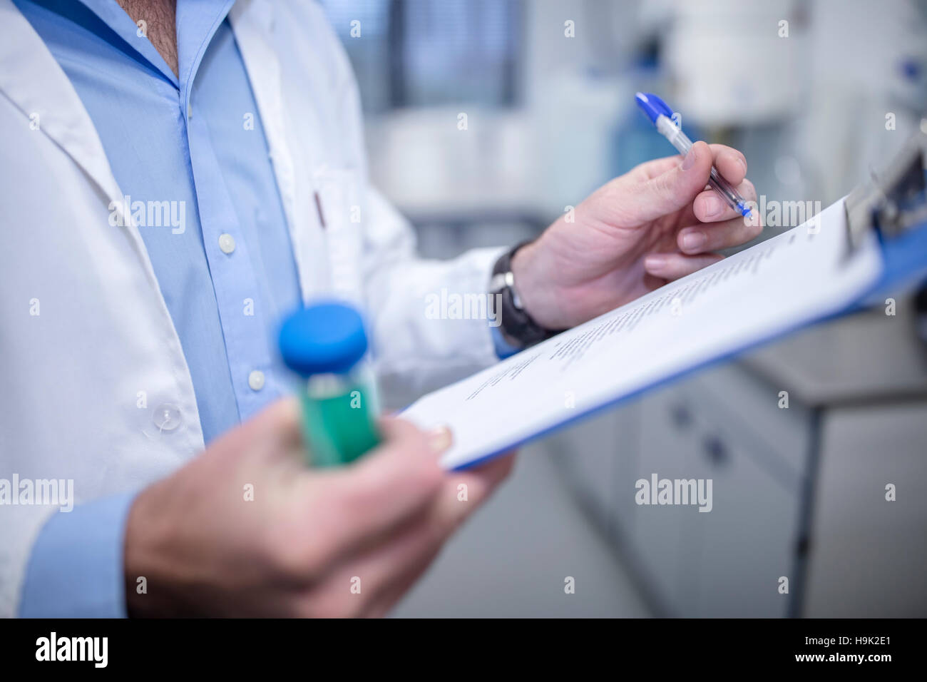 Scientist with clipboard and test tube working in laboratory Stock ...