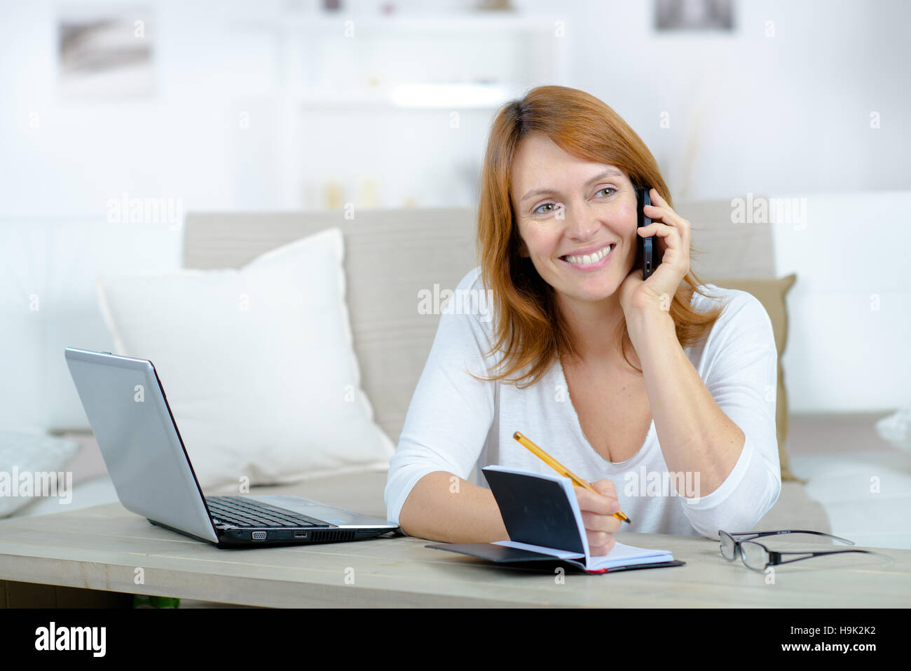 smiling woman on a phone call using laptop Stock Photo - Alamy