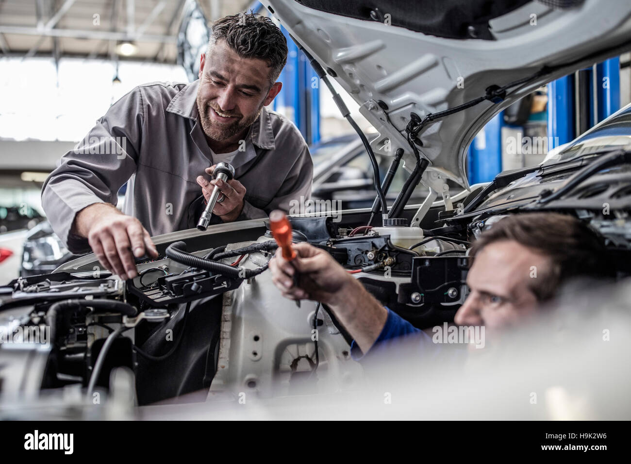 Two car mechanics in a workshop repairing car together Stock Photo - Alamy