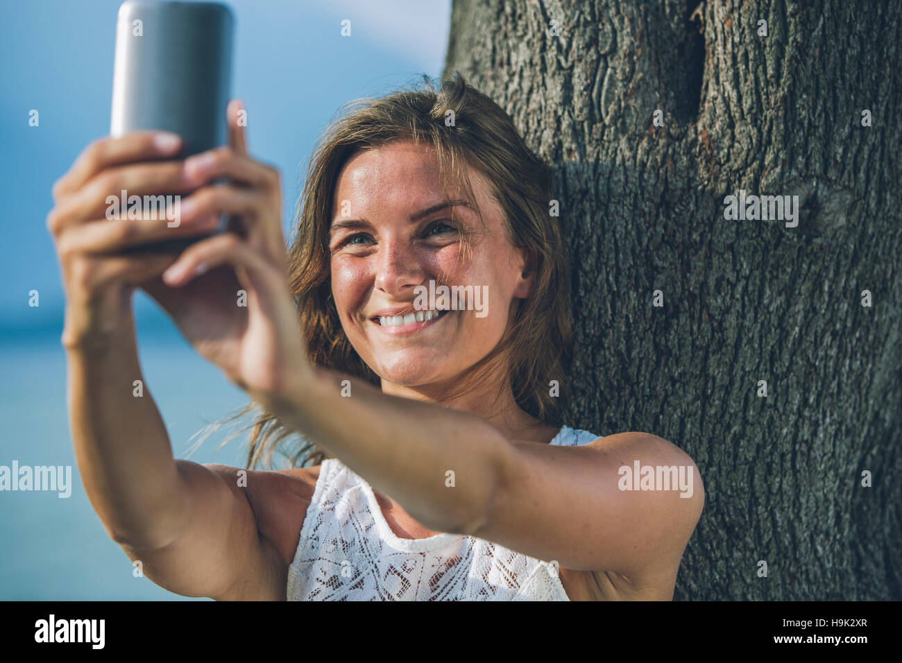 Young woman taking a selfie at a tree Stock Photo - Alamy