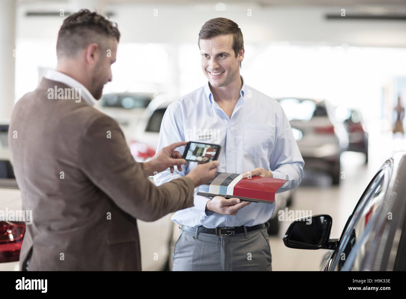 Client taking cell phone picture at car dealership Stock Photo - Alamy