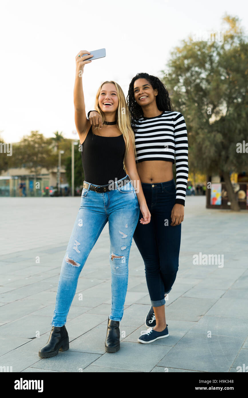 Two young women taking a selfie on square Stock Photo - Alamy