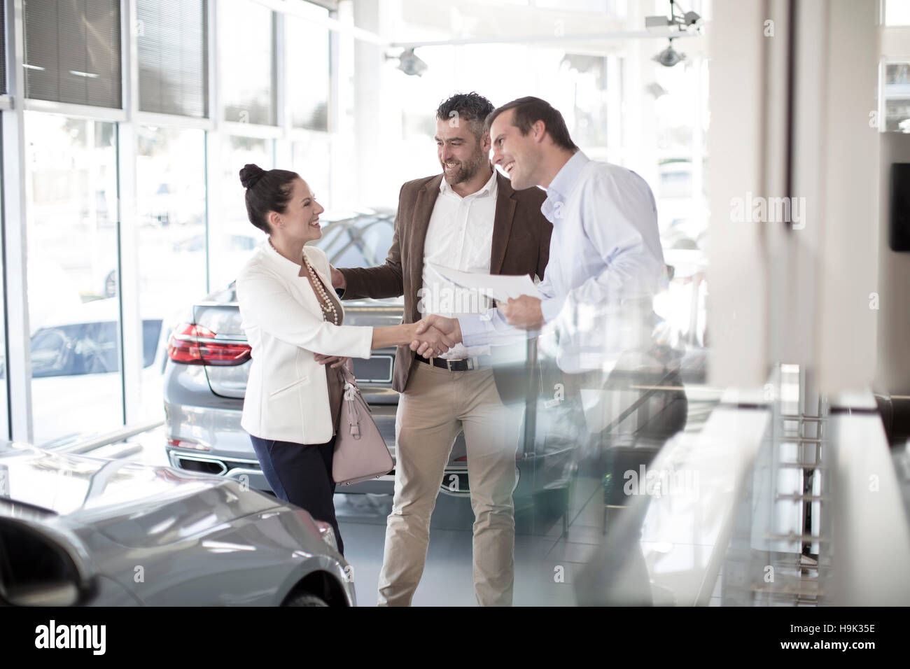 Car dealer shaking hands with woman in car dealership Stock Photo - Alamy