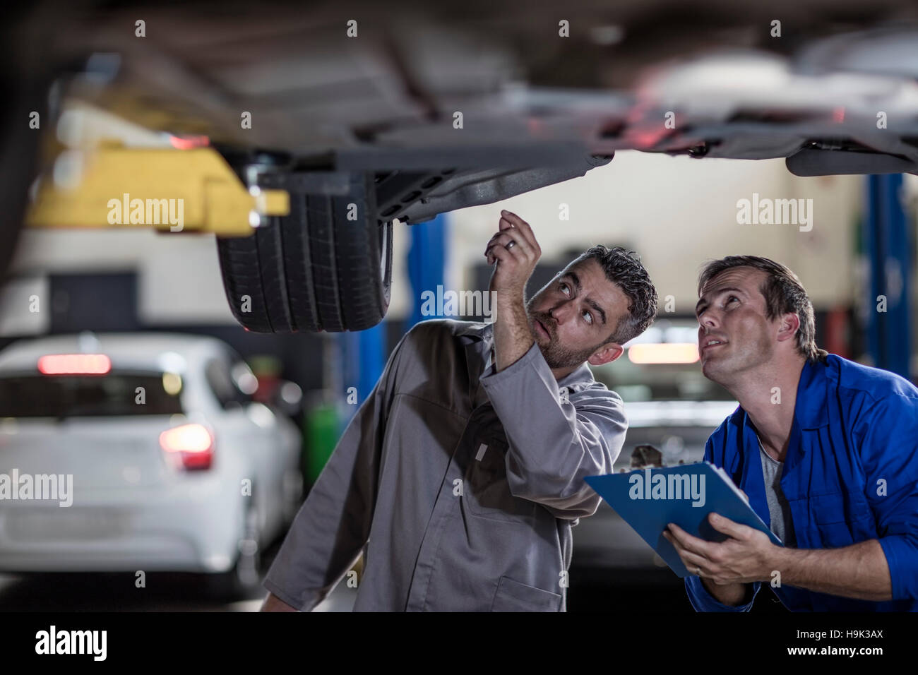 Two car mechanics in a workshop examining car together Stock Photo - Alamy