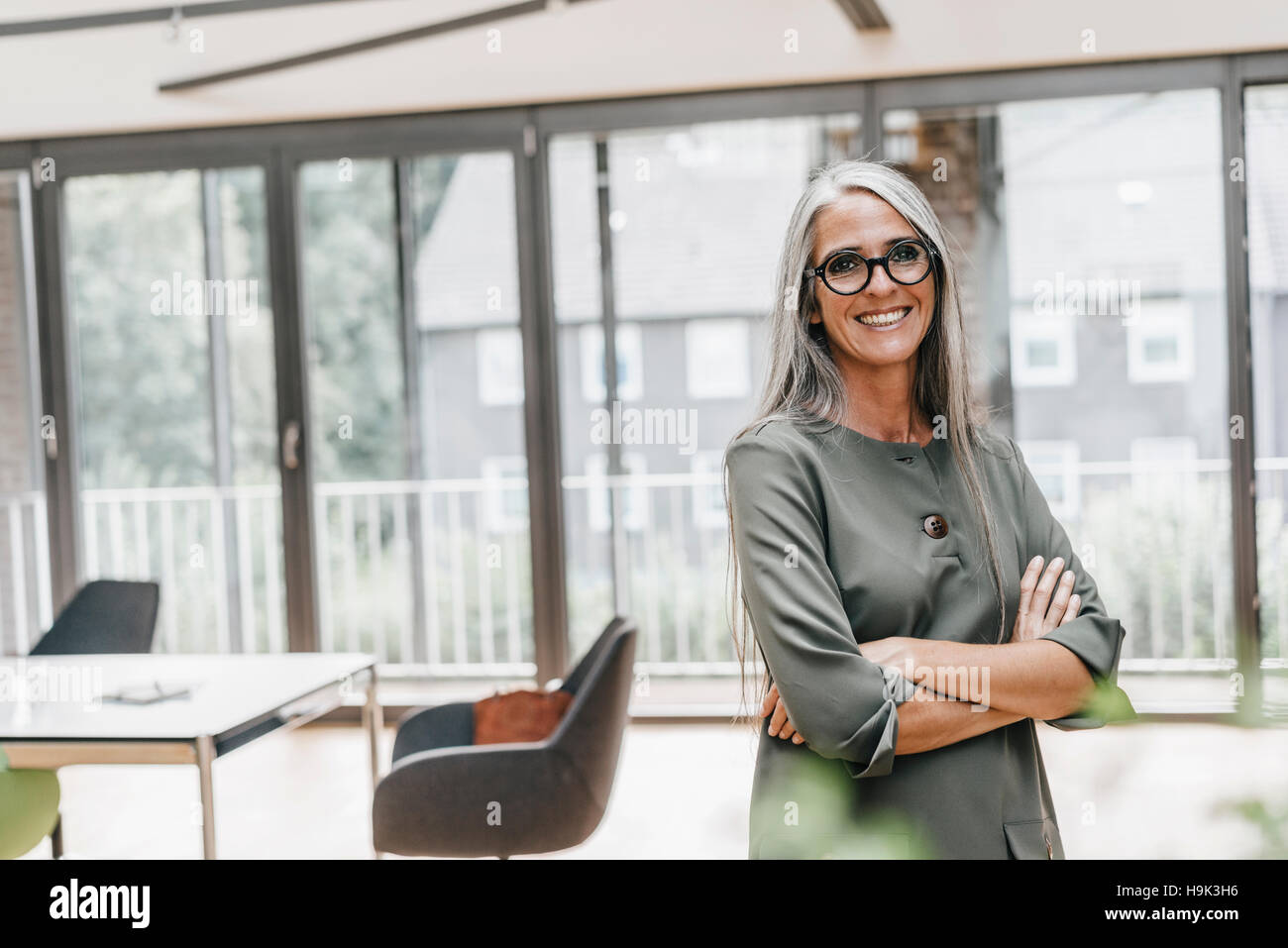 Portrait of smiling woman with long grey hair in office Stock Photo - Alamy