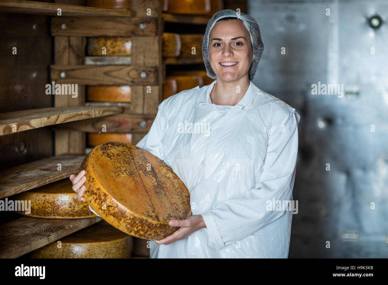 Cheese factory worker proudly holding loaf of cheese Stock Photo - Alamy