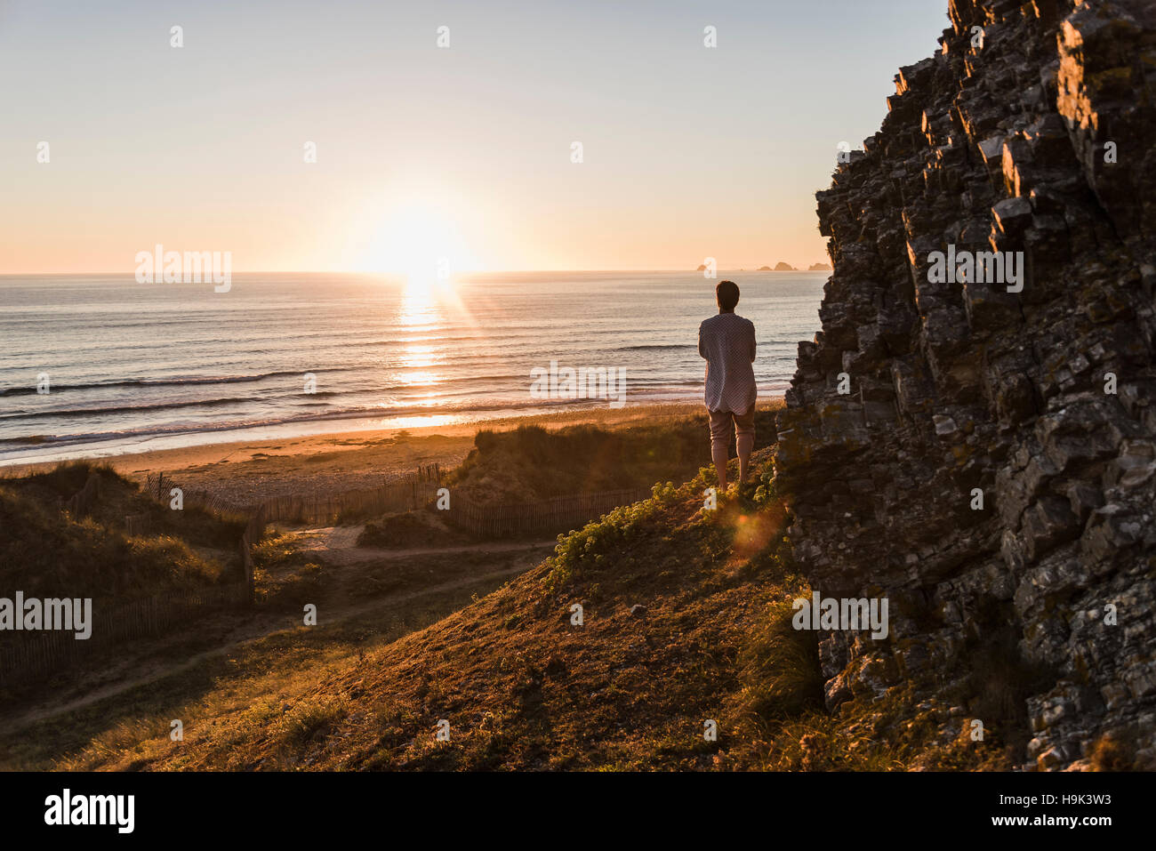 Back view of woman standing on cliff watching sunset Stock Photo - Alamy