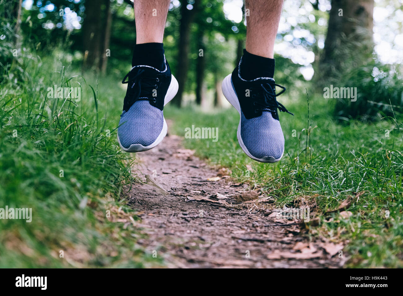 Shoes of jogger jumping on forest track Stock Photo - Alamy