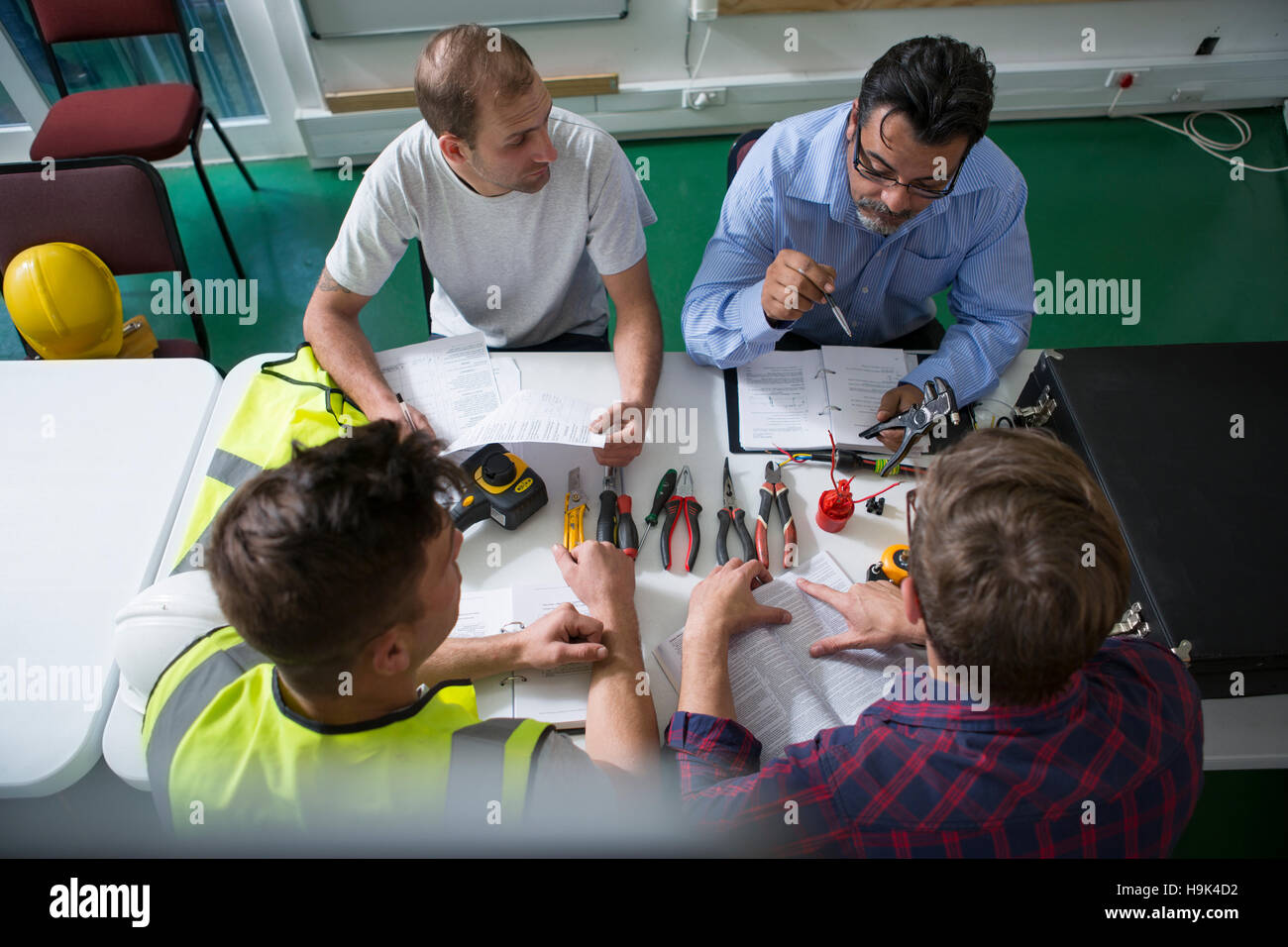 Electrician instructor sitting with students at table Stock Photo - Alamy