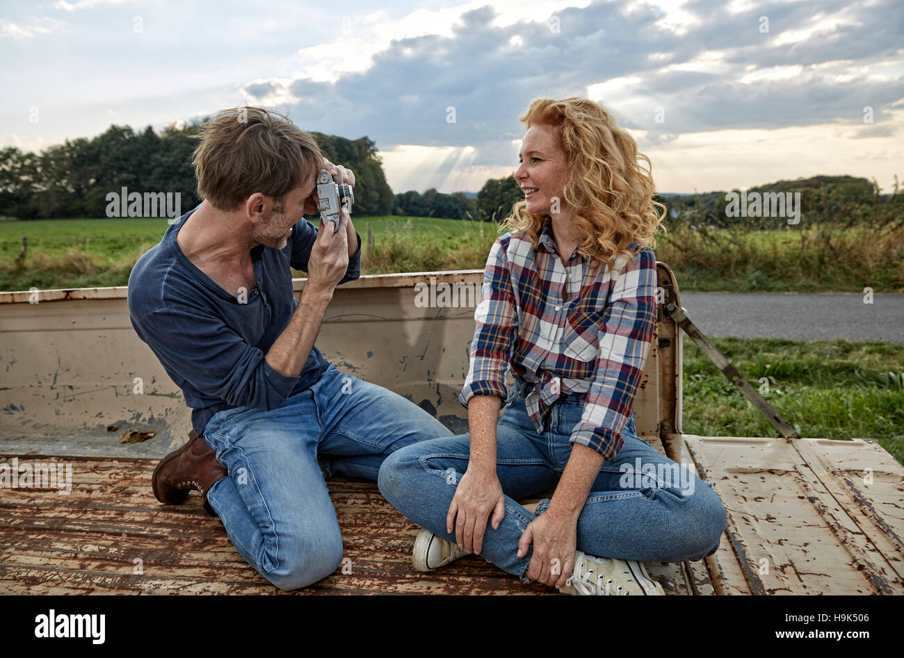Man taking picture of woman on pick up truck Stock Photo - Alamy