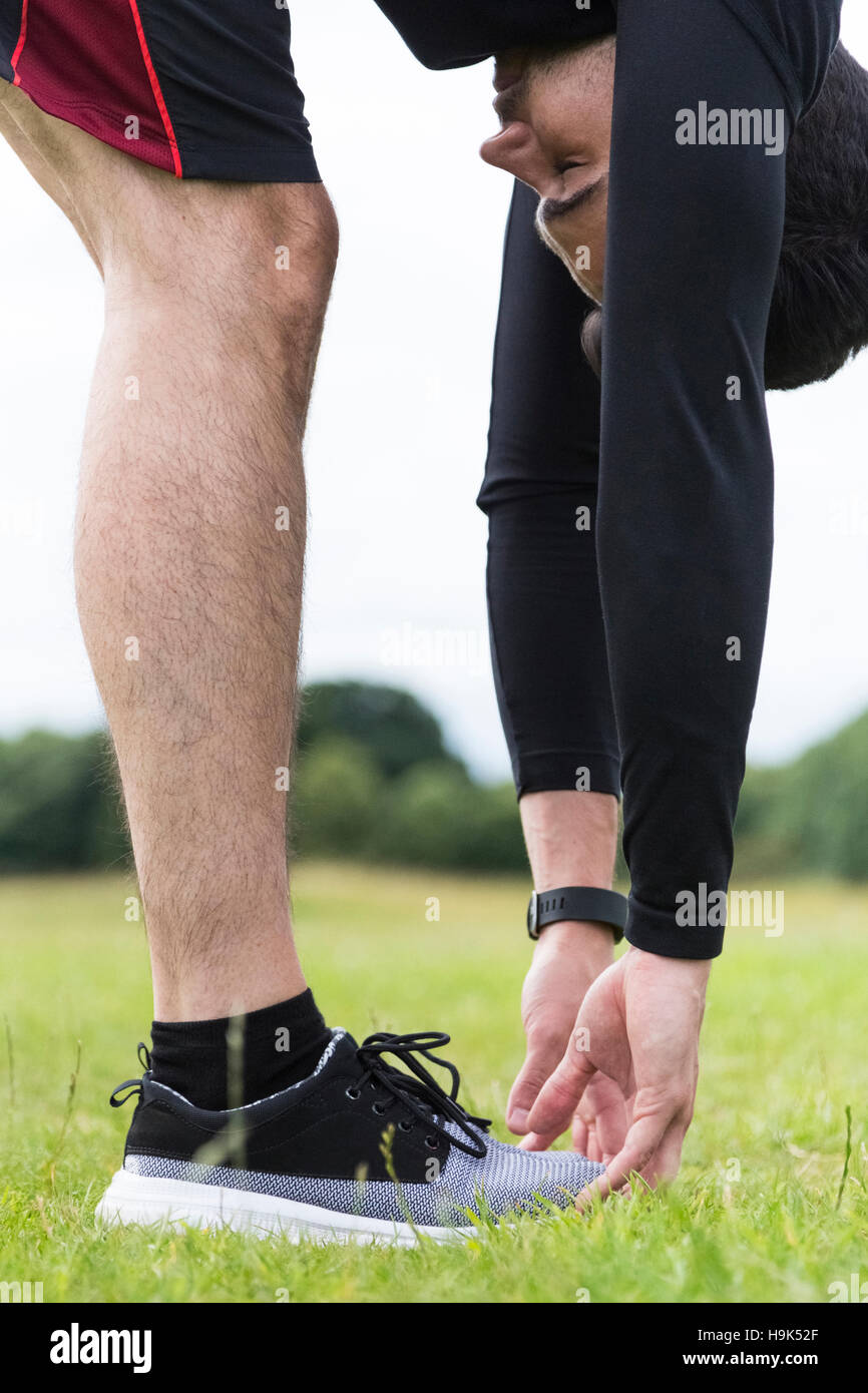 Athlete stretching in grass Stock Photo - Alamy