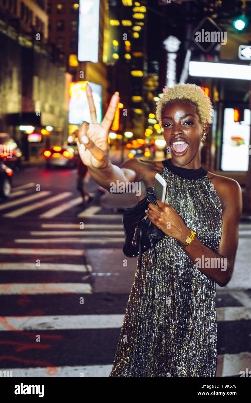 USA, New York City, young woman showing victory sign on Times Square at ...
