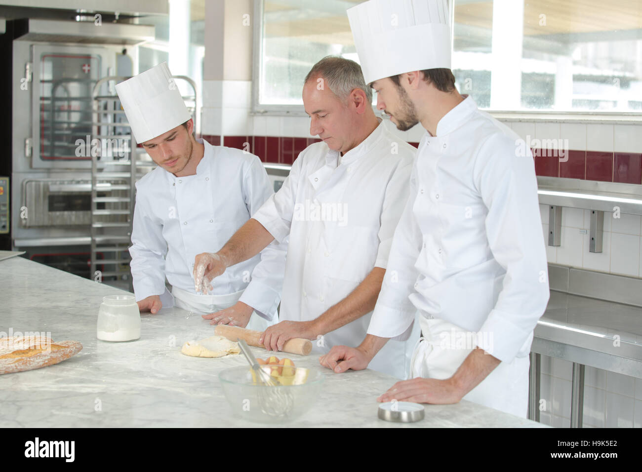 head chef showing two trainees how to prepare dough Stock Photo - Alamy
