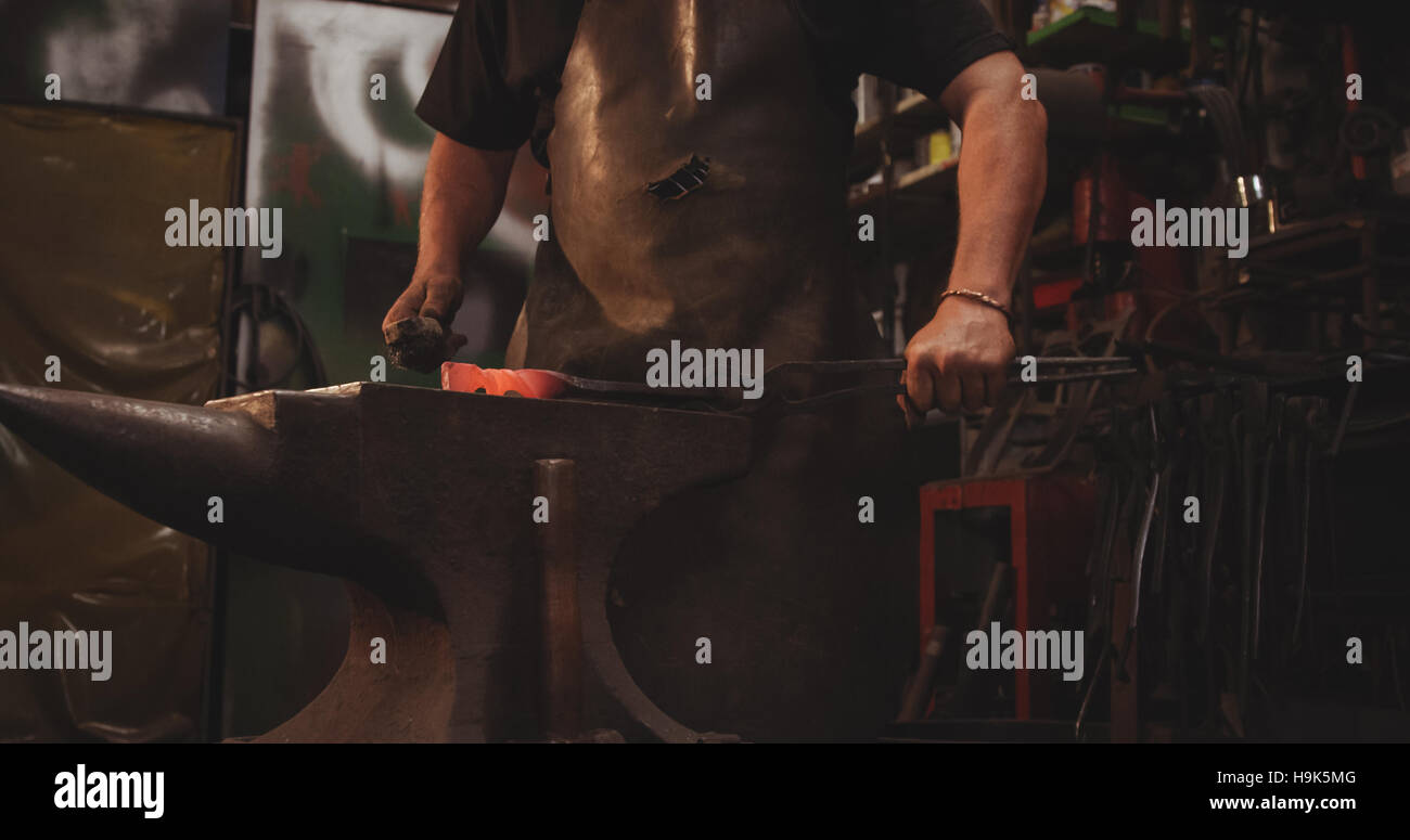 Blacksmith working on hot metal using hammer to shape Stock Photo - Alamy