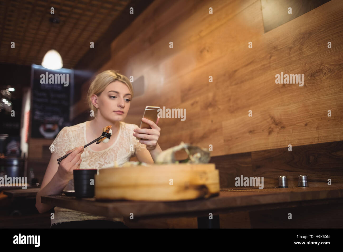 Woman using mobile phone while eating sushi Stock Photo - Alamy
