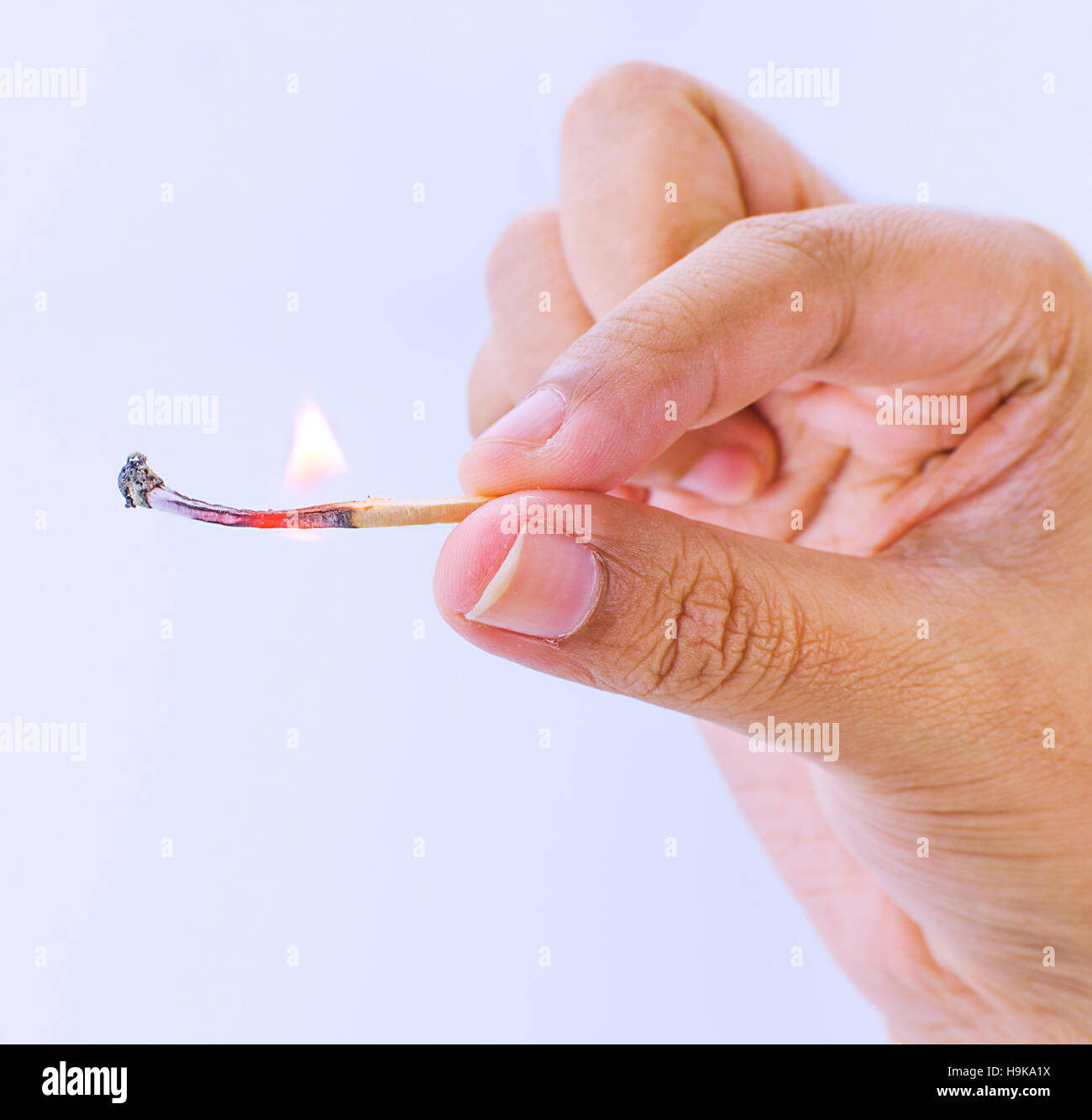 Hand holding a fired matchstick on a white background Stock Photo - Alamy