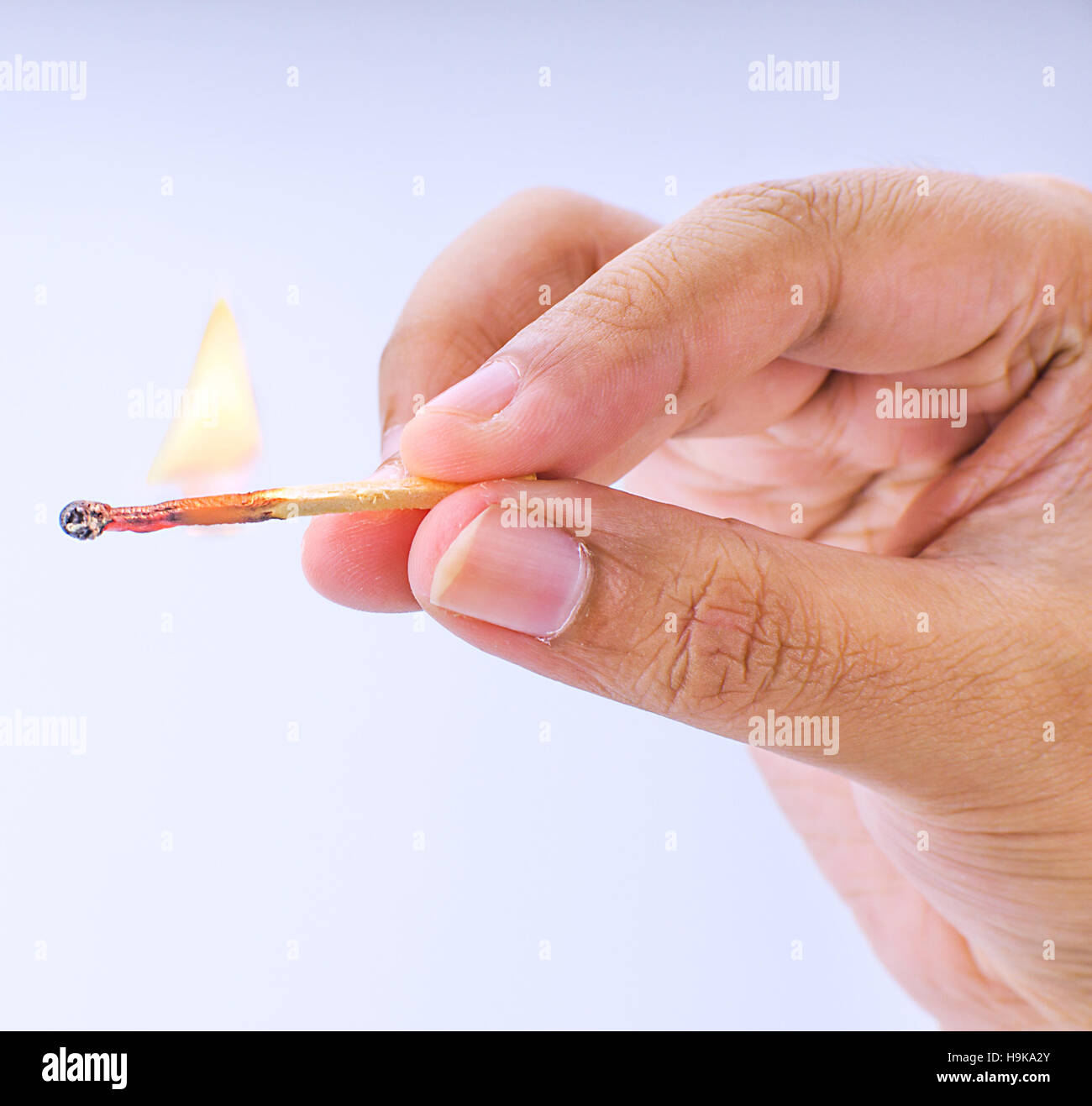 Hand holding a fired matchstick on a white background Stock Photo - Alamy