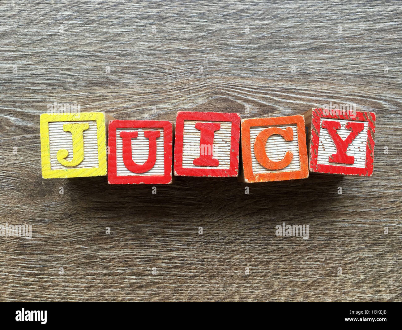 Alphabet wood blocks making the word JUICY Stock Photo - Alamy