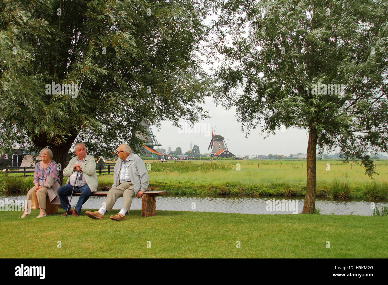 Senior citizens sit on a bench next to a stream image in landscape ...