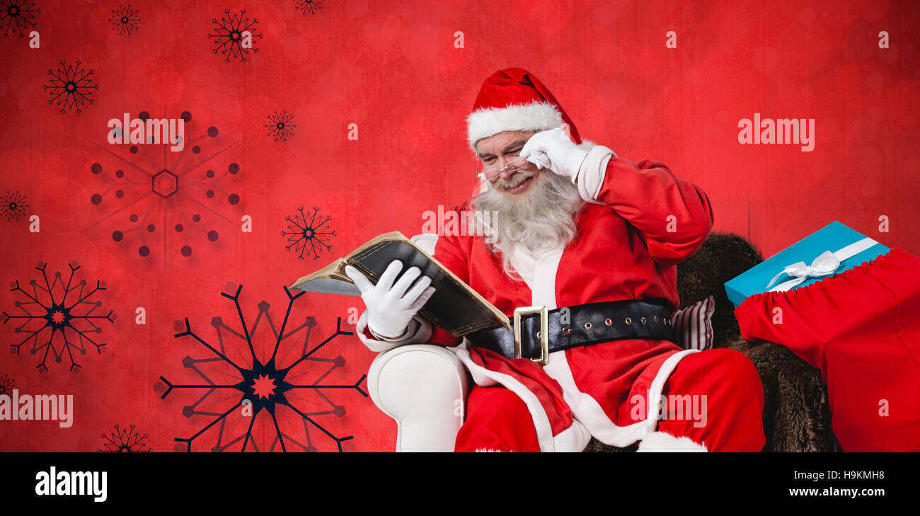 Composite image of santa reading bible with sack of christmas present ...