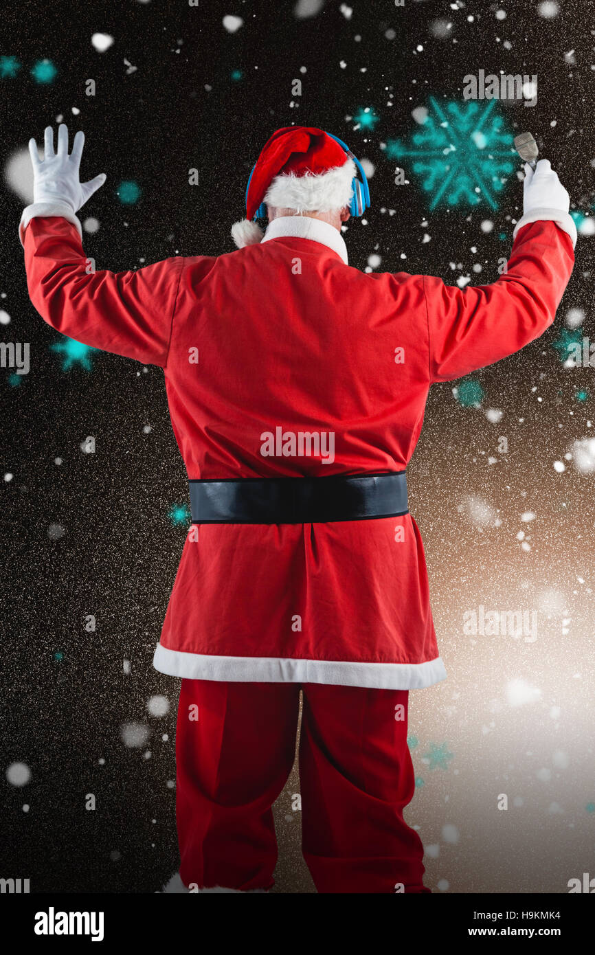 Composite image of rear view of santa claus listening to music Stock ...