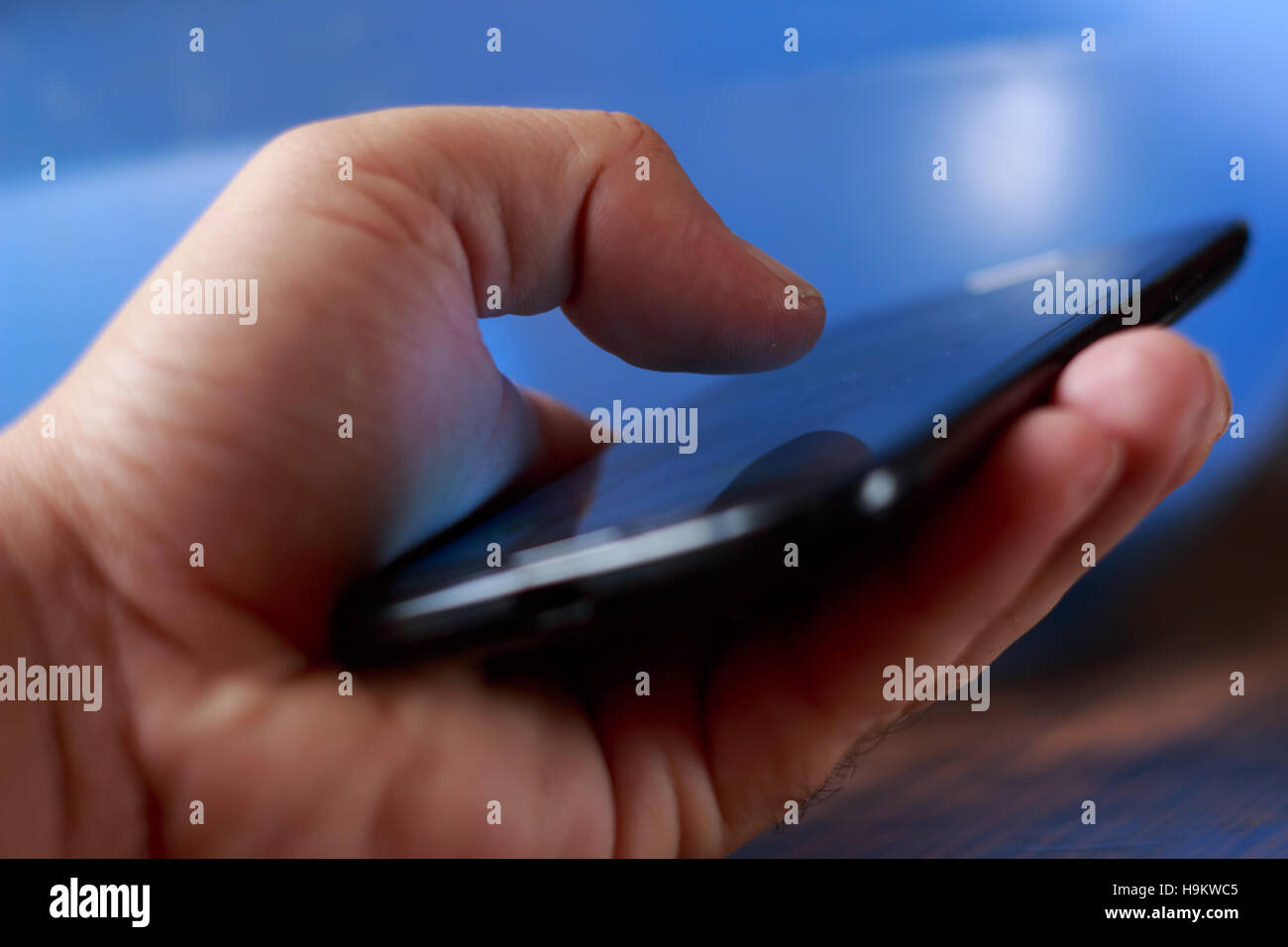 Closeup of young boys hand using smartphone. Blue blurred background ...