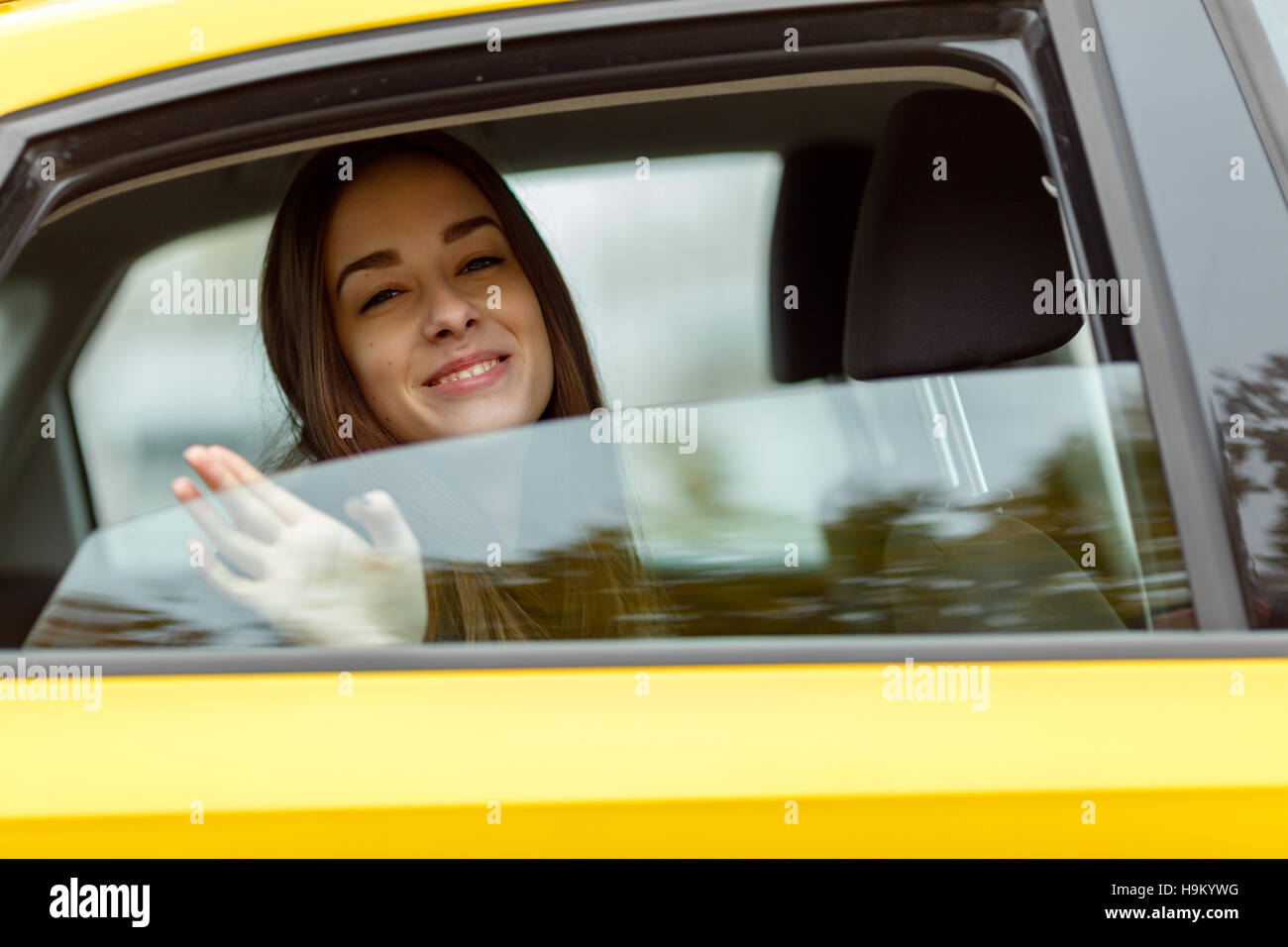 Girl waves hand from window Stock Photo - Alamy