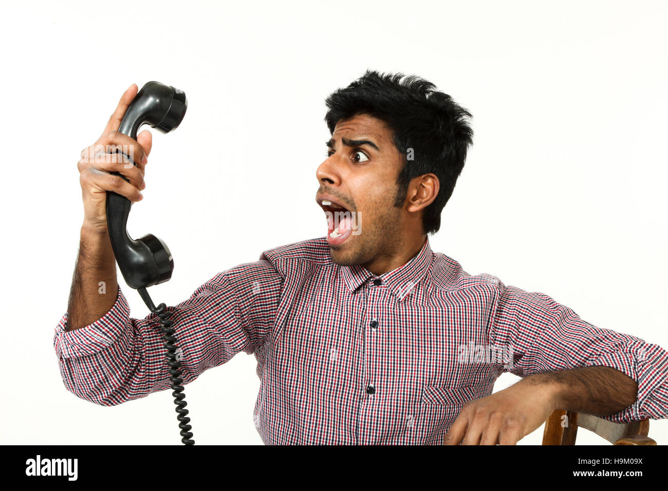 young man struggling with a crazy telephone , portrait on white ...