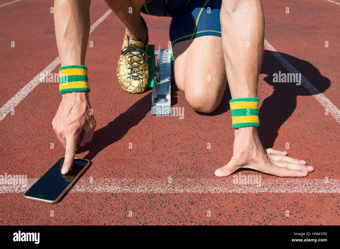 Athlete crouching at the starting line of a running track wearing ...
