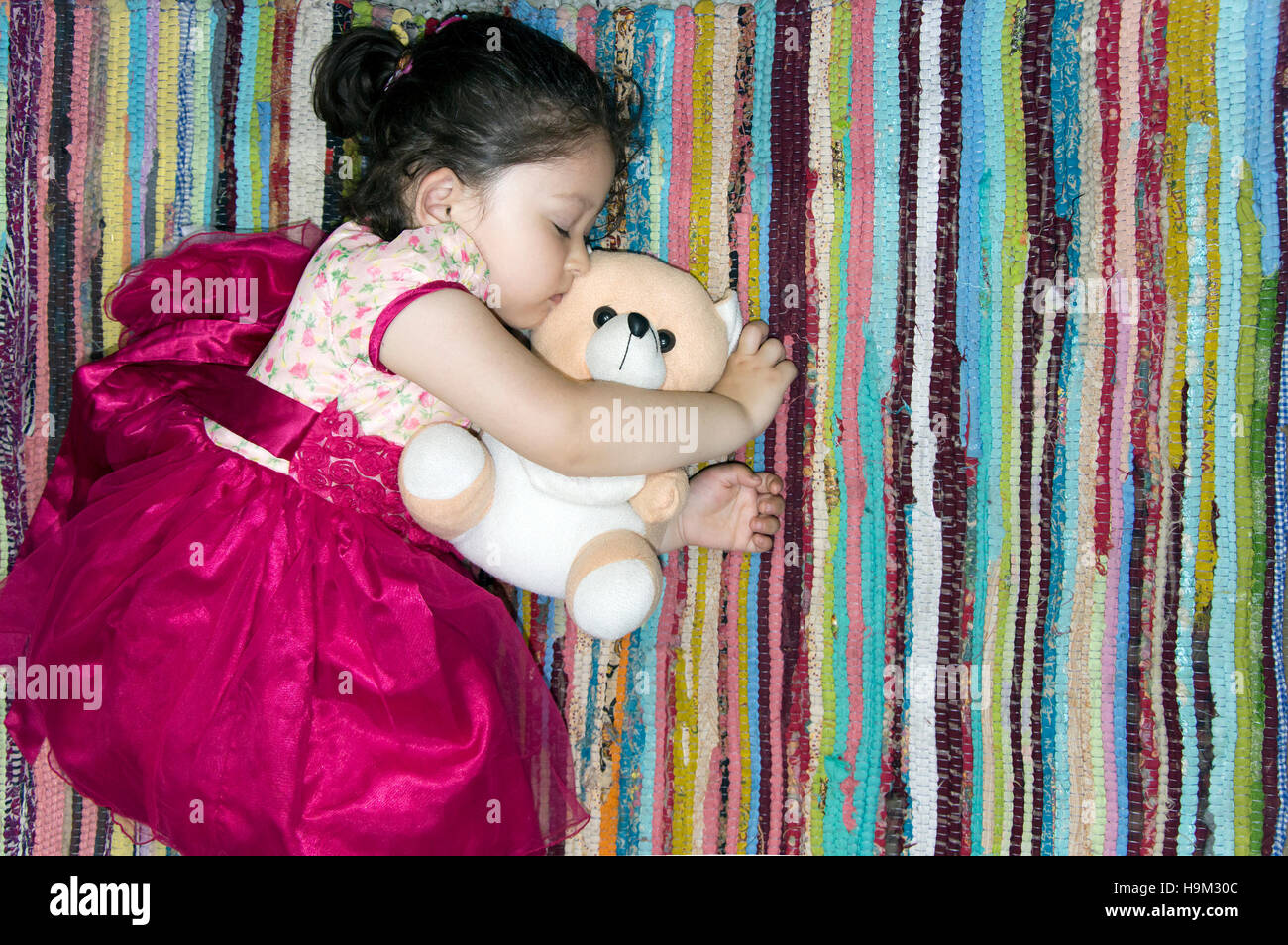 Little girl sleeping on a colorful rug Stock Photo - Alamy