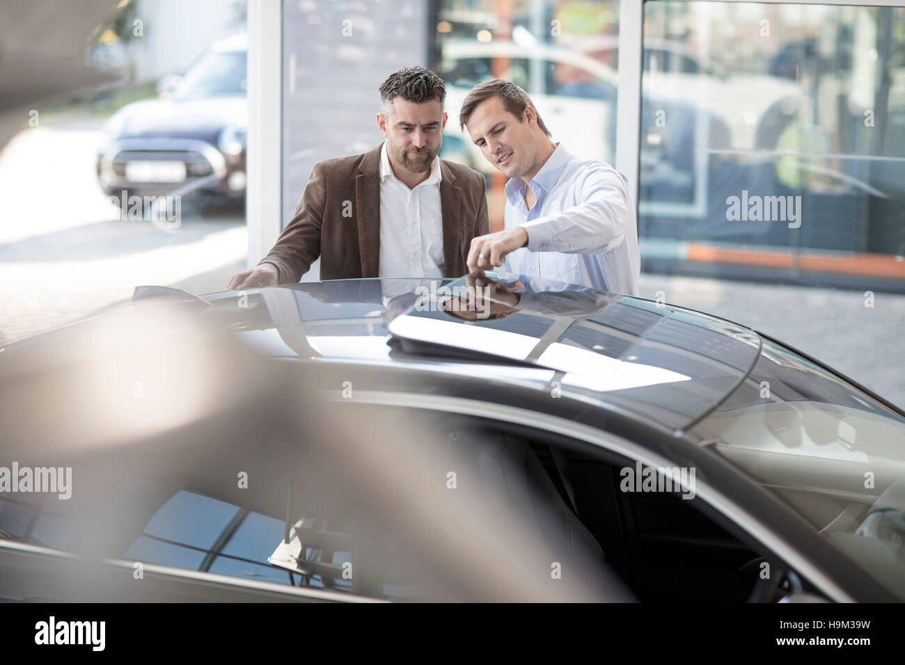 Car dealer talking to client at car dealership Stock Photo - Alamy
