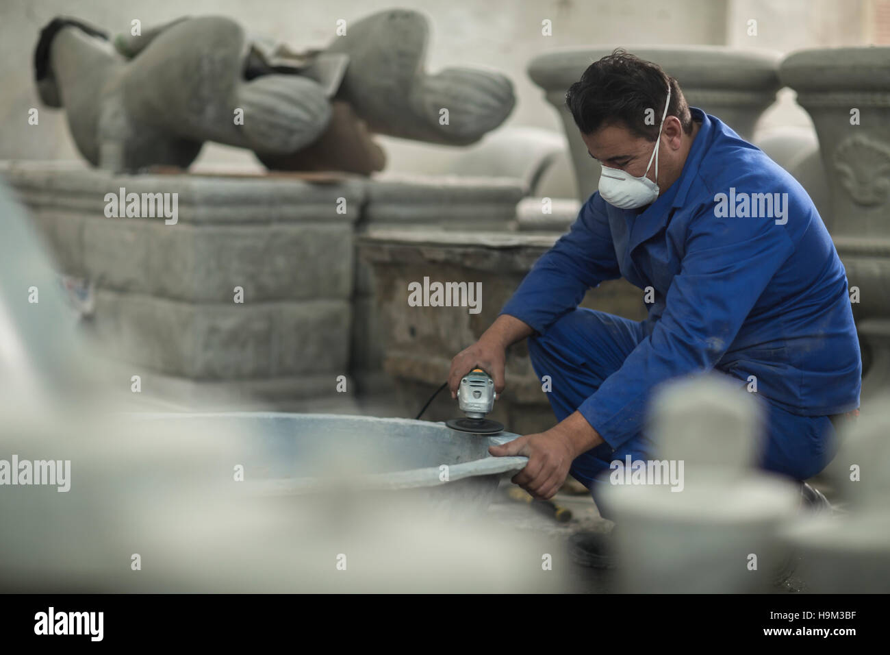 Worker grinding object in industrial pot factory Stock Photo - Alamy