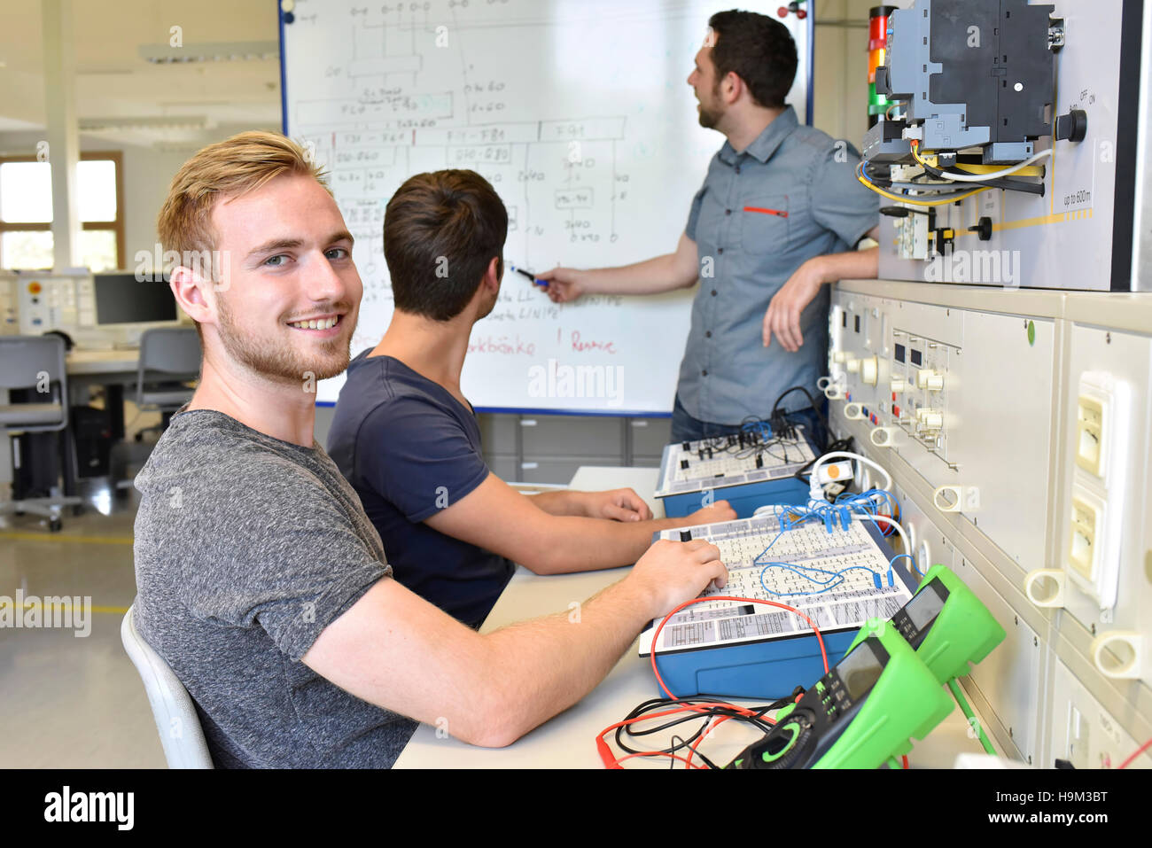 Portrait of smiling student with technical instructor at whiteboard ...