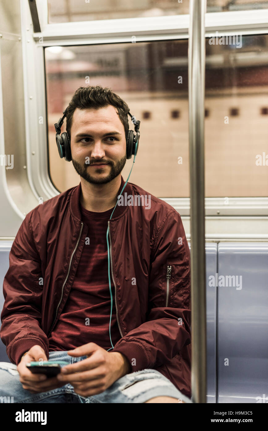 Young man sitting in subway wearing headphones Stock Photo - Alamy