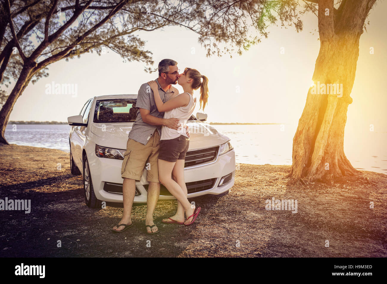 Couple on a road trip taking a break kissing each other Stock Photo - Alamy