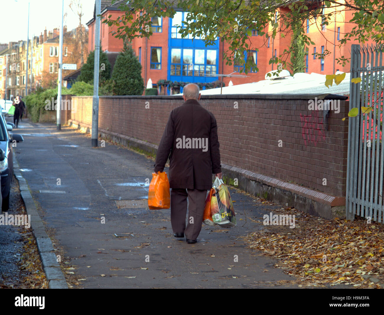 single old man alone walking carrying shopping in urban cityscape Stock ...
